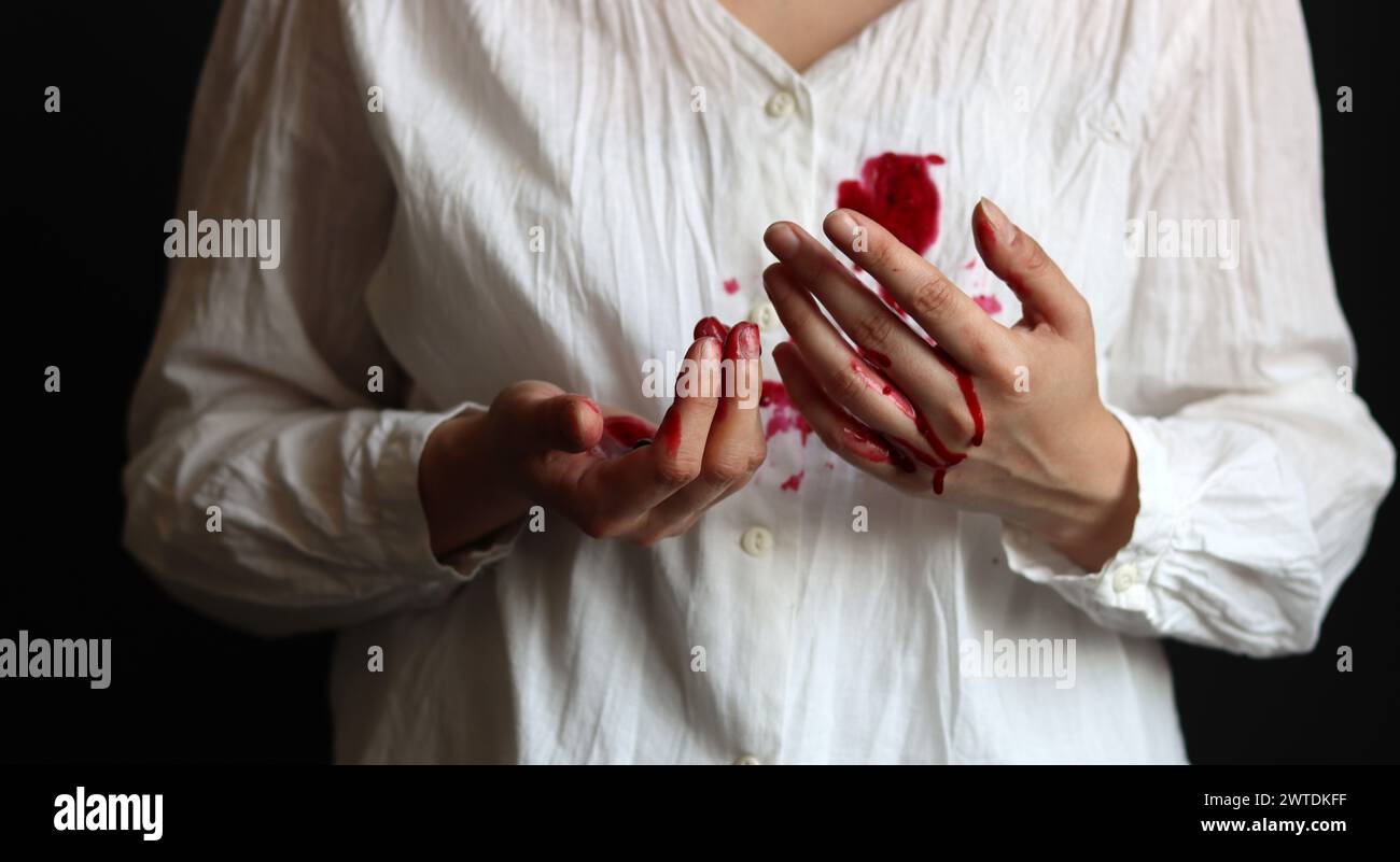 Female hands with blood on a black background with copy space. The ...