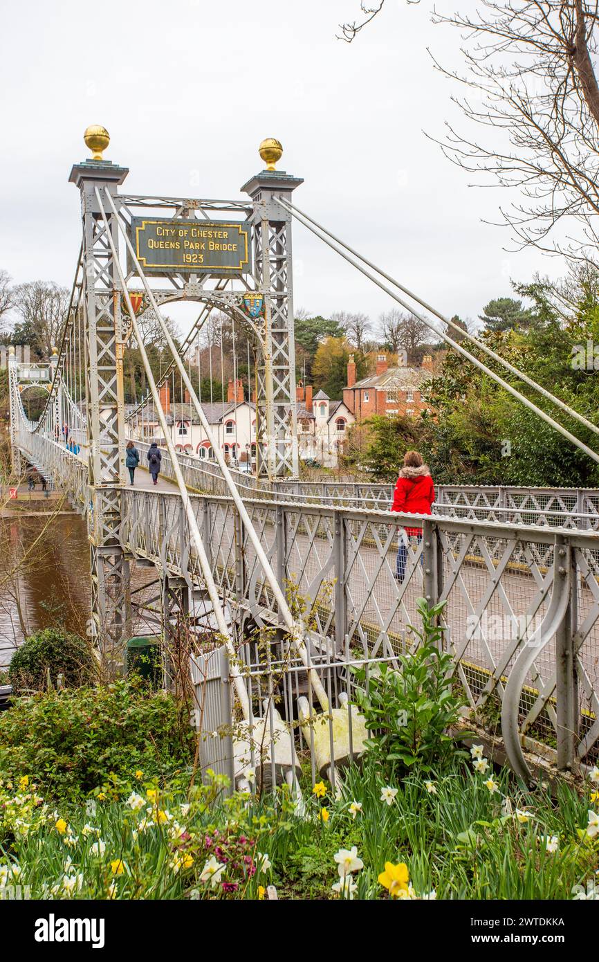 Woman in red coat walking over the Queens Park Bridge over the river ...