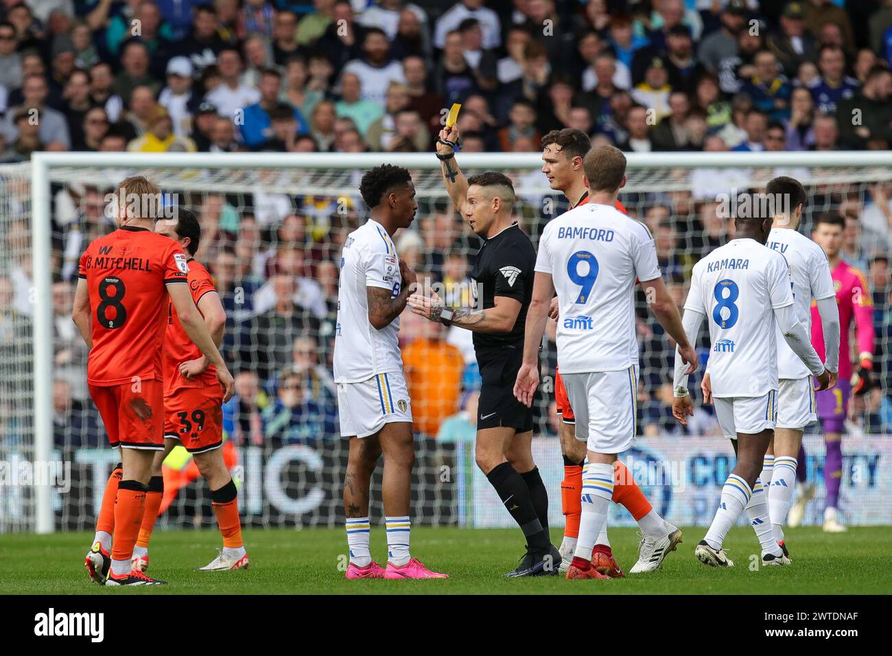 Referee Stephen Martin awards a yellow card to Júnior Firpo of Leeds ...