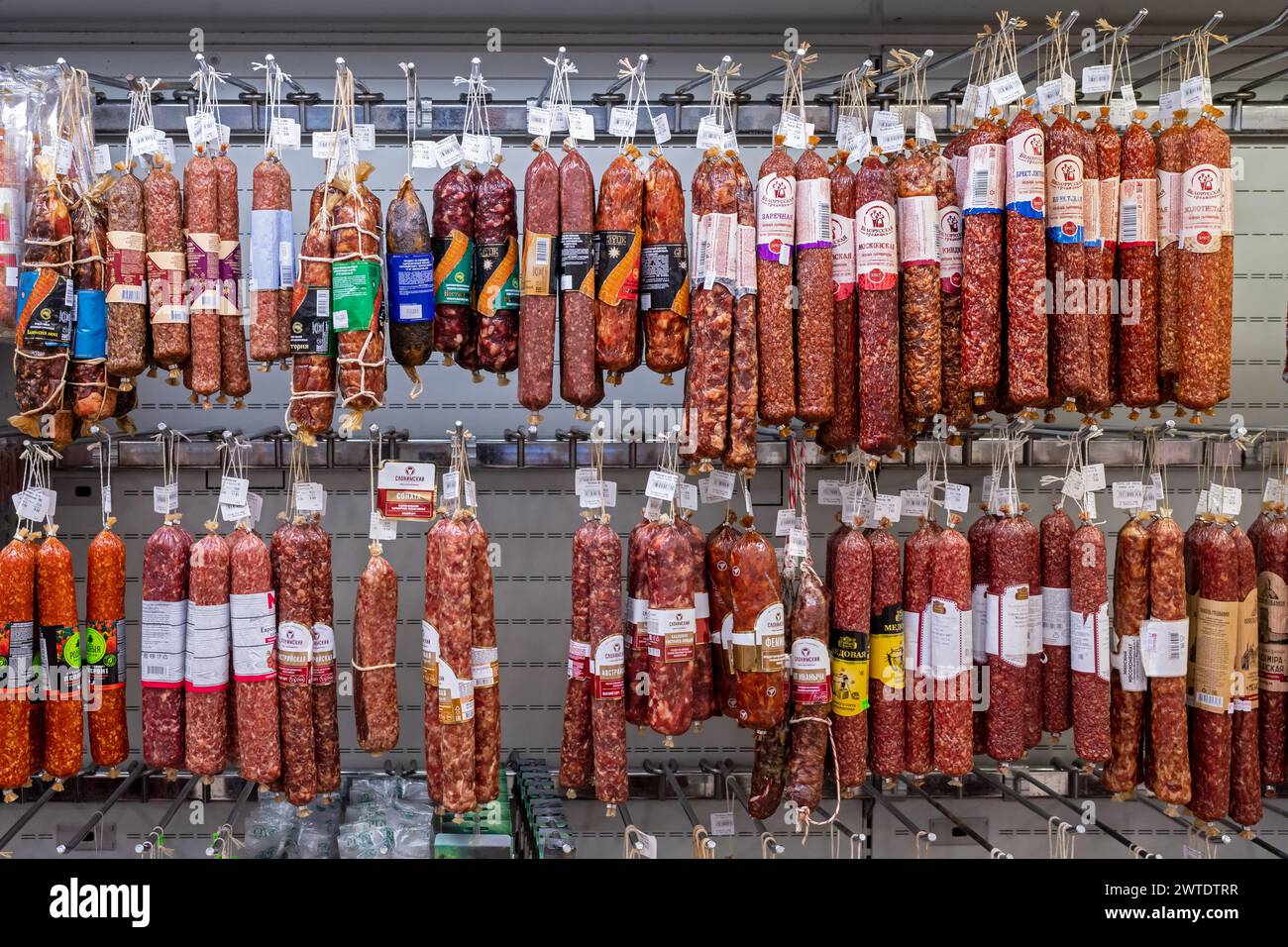 Various salami, smoked sausages on display in grocery store. Wide ...