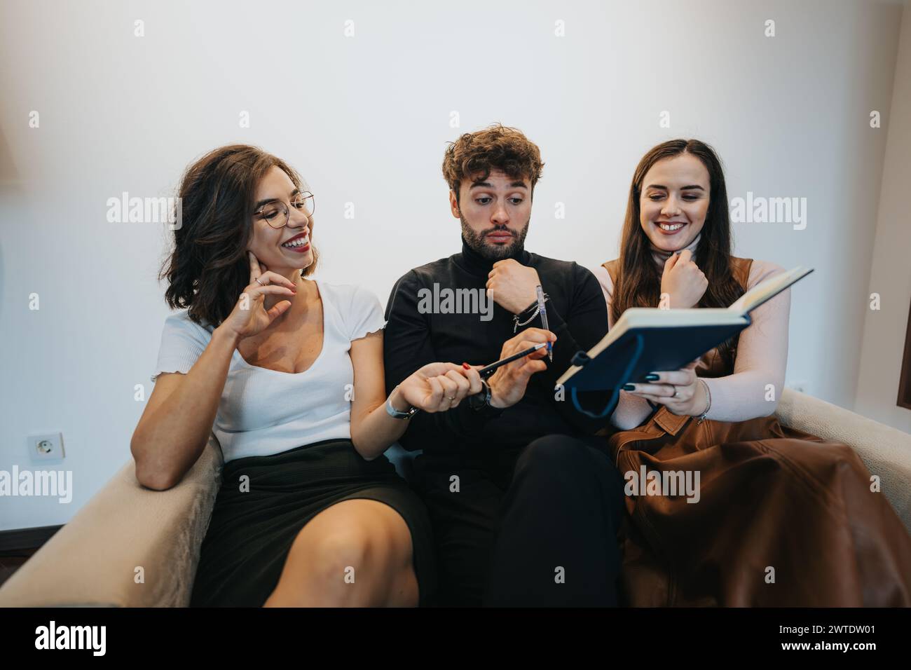 Three friends sharing a laugh while looking at a tablet, casual meeting ...