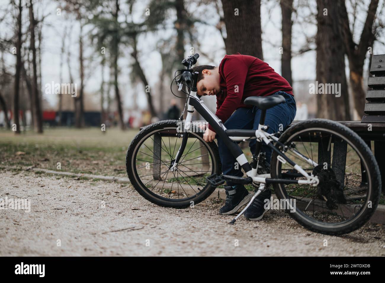 Exhausted young cyclist taking a break on a park bench with bike Stock ...