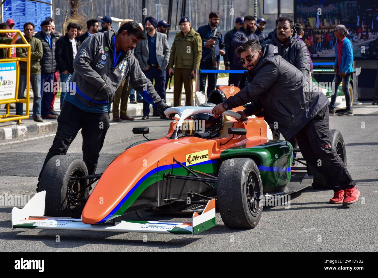 Srinagar, India. 17th Mar, 2024. Officials push a racing car during a motorsport event organized ...