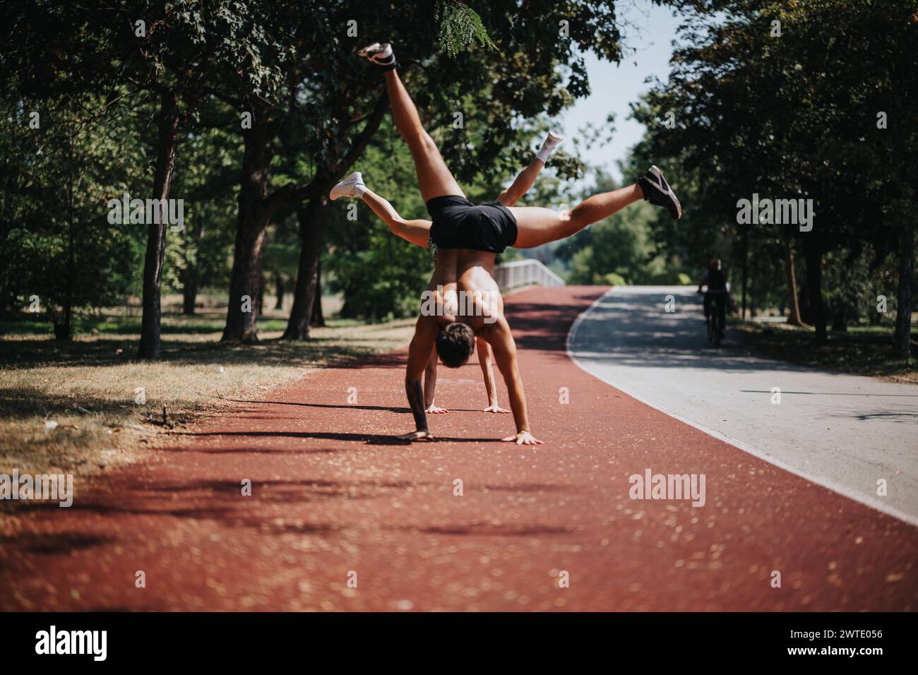 Fit sportspeople, a man and a woman, practice cartwheels in a sunny ...