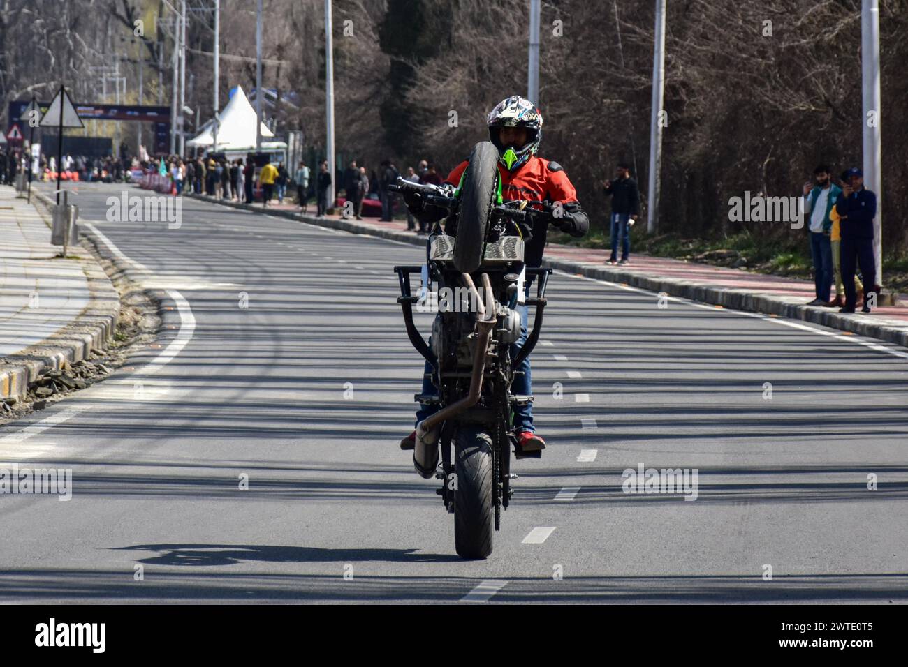 Srinagar, India. 17th Mar, 2024. A professional bike rider performs a stunt during a motorsport ...