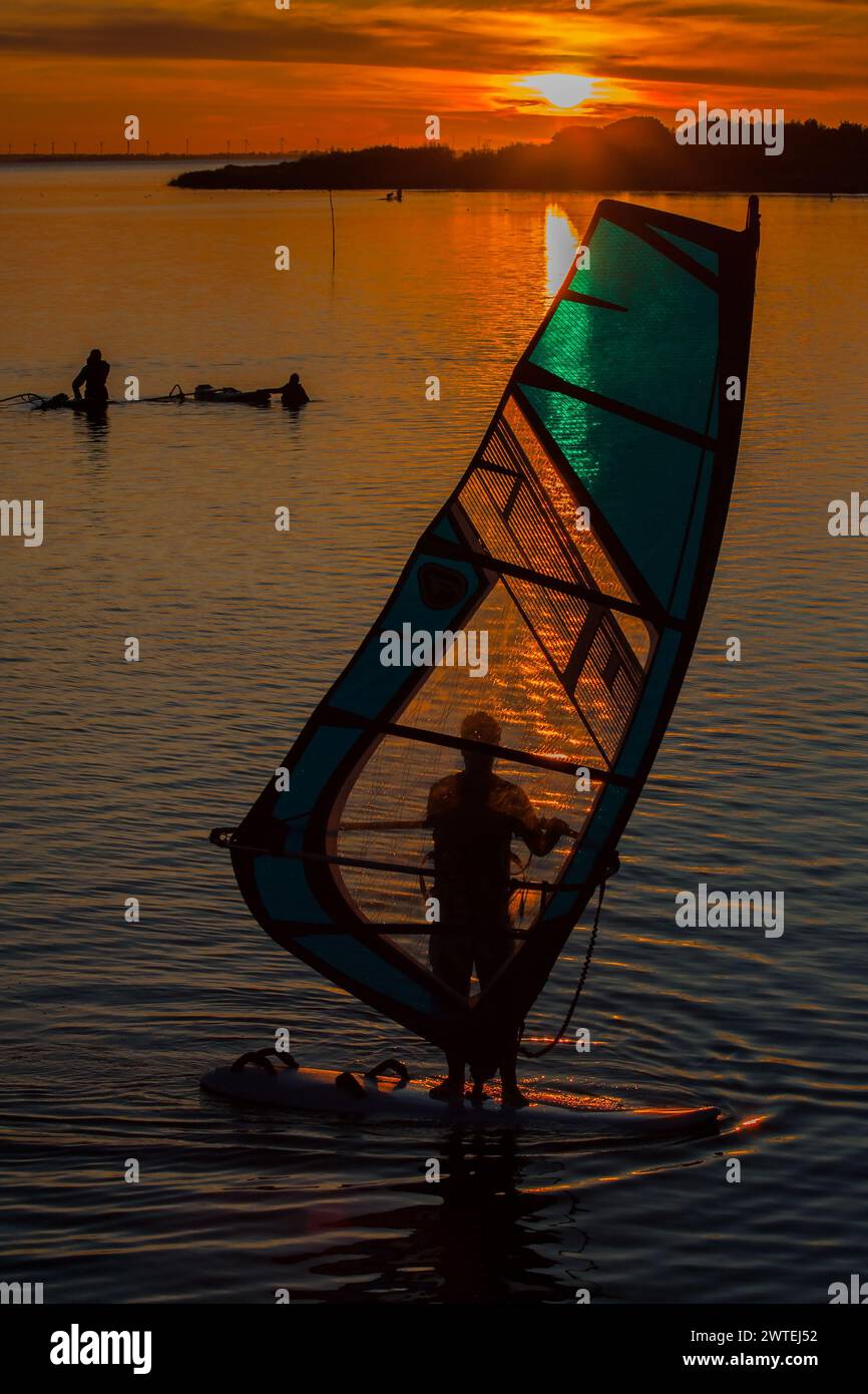 Windsurfing on a quiet lake at sunset, holiday sport Stock Photo - Alamy