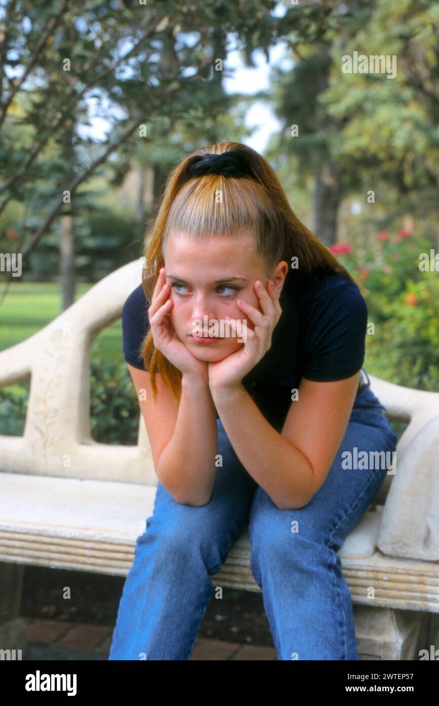 A young blonde moody girl teenager sitting on a park bench Stock Photo ...