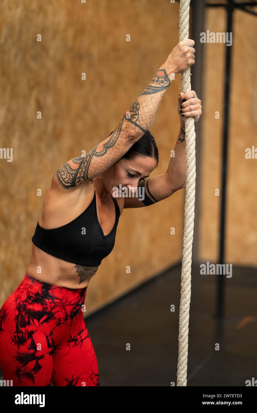 Tired sportive woman climbing a rope in a gym Stock Photo - Alamy