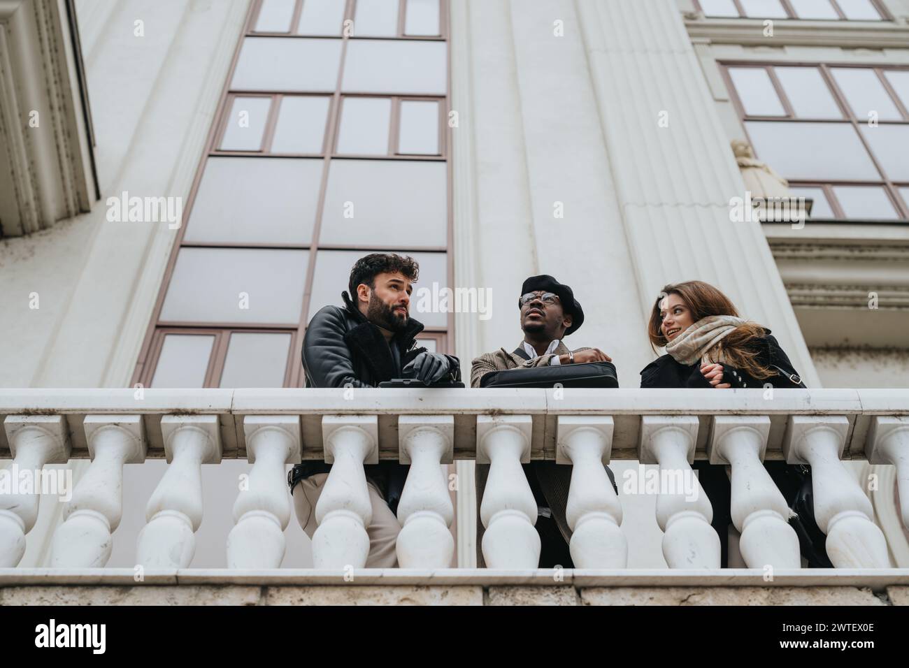 Three friends enjoying time together overlooking from a classic balcony ...