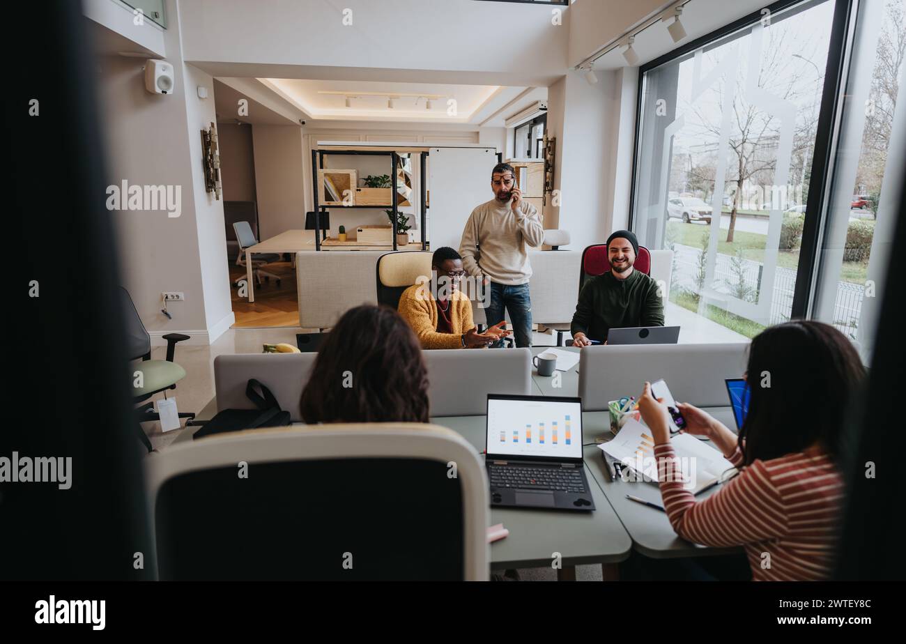 A multiethnic group of coworkers collaborates around a table in a ...