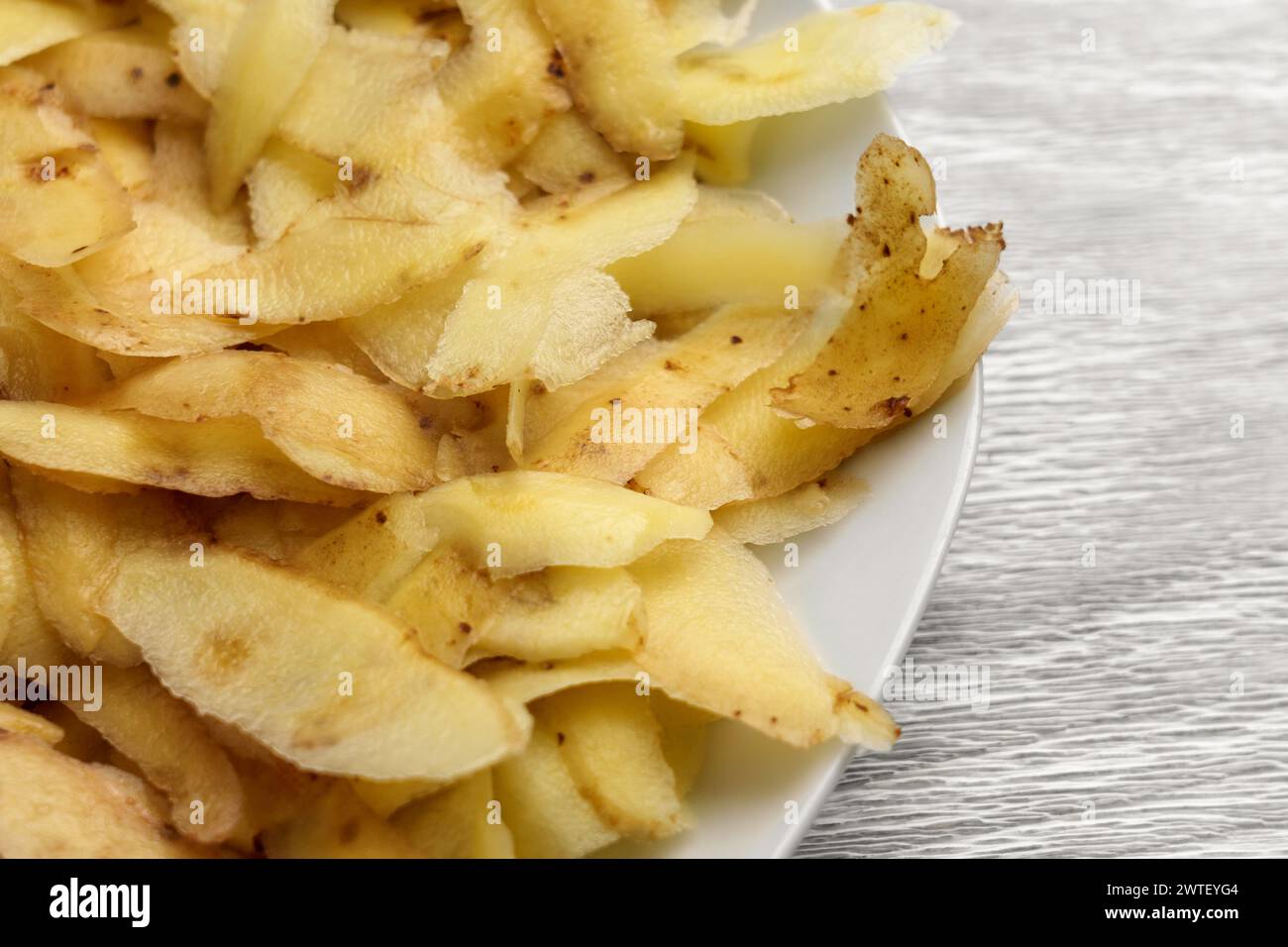 Potato peel on white kitchen plate. Food waste close up Stock Photo - Alamy