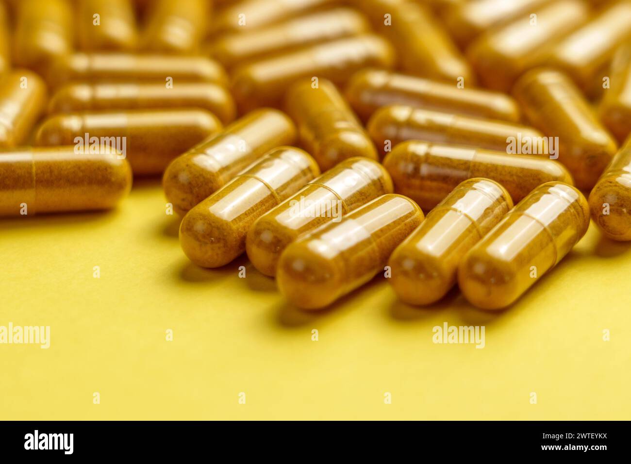 Yellow turmeric (curcuma) supplement capsules on a creative colour ...