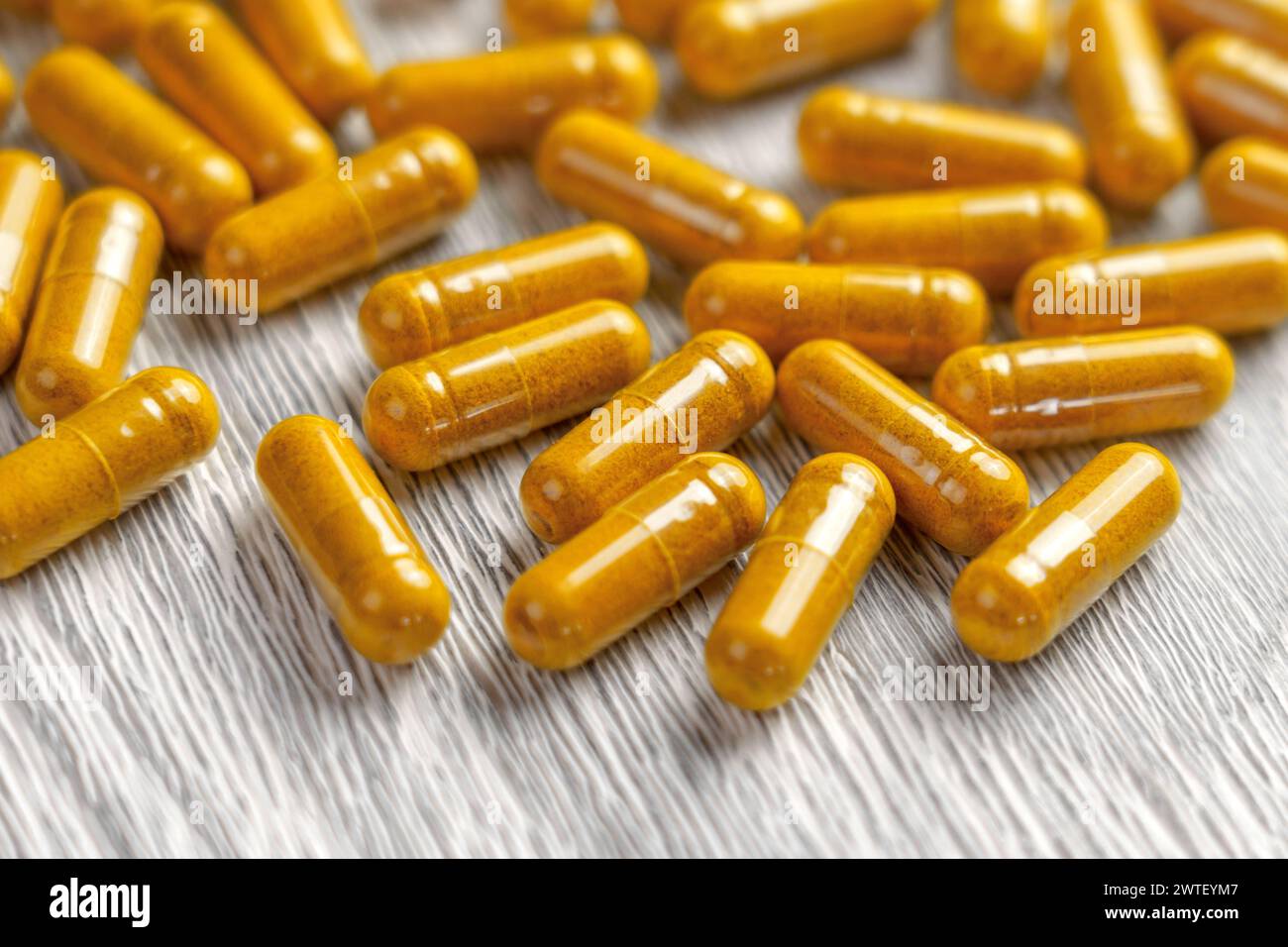 Curcuma herbal medicine pills in wooden plate. Yellow medicinal ...