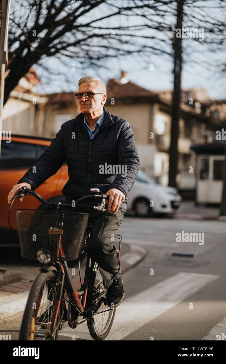 Senior man enjoying a leisurely bike ride in a quiet urban setting ...