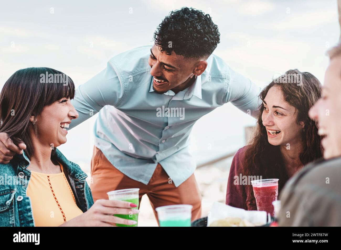 Joyful friends share a laugh - seaside backdrop enhances the convivial ...