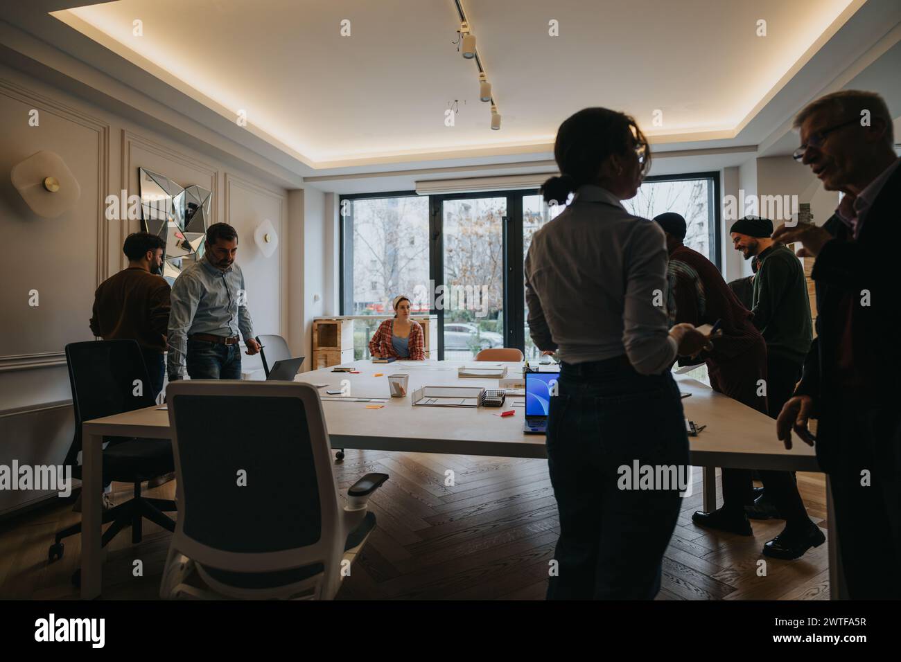 A group of employees congregate for a casual business meeting in a well ...