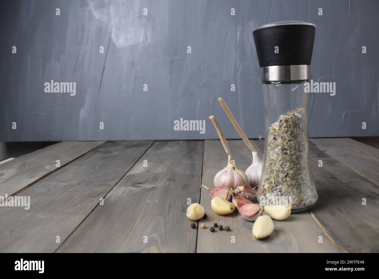 A salt shaker with seasoning and salt garlic lies next to it on a gray ...