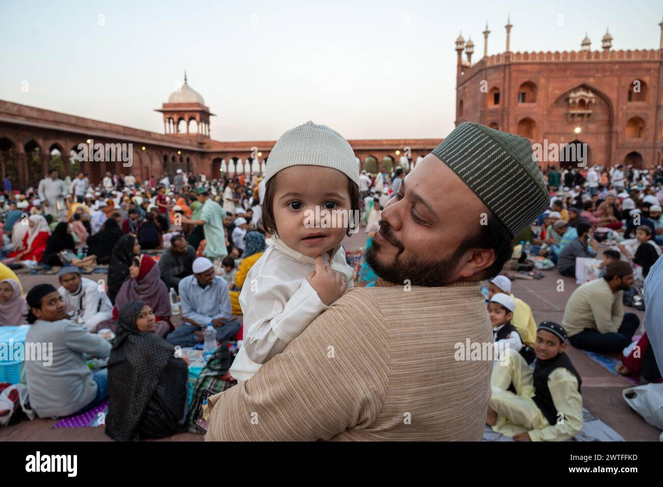 A Muslim man, carries his child as he waits for sunset to break the ...
