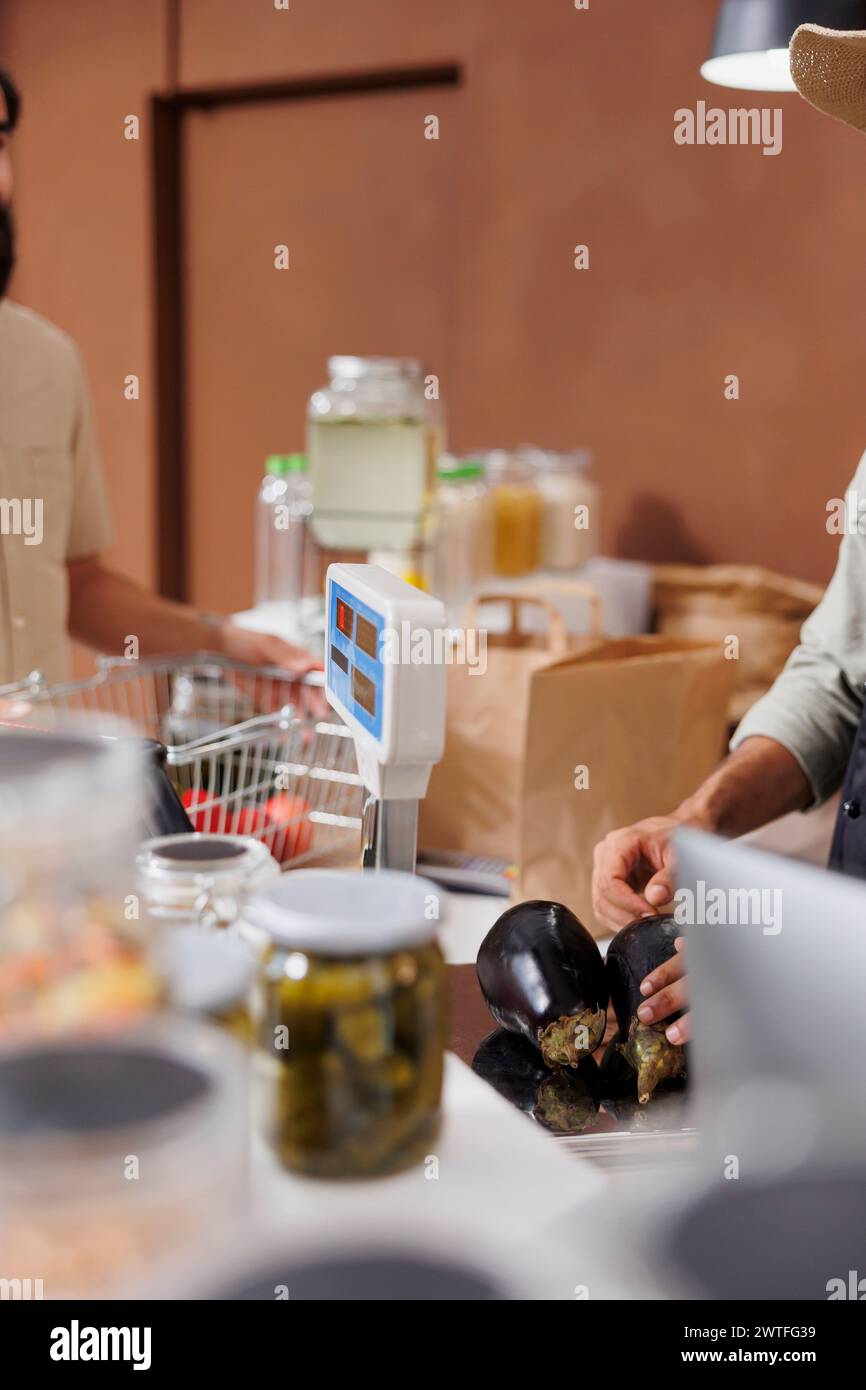 Shopkeeper putting fresh produce on measuring scale and selling natural ...