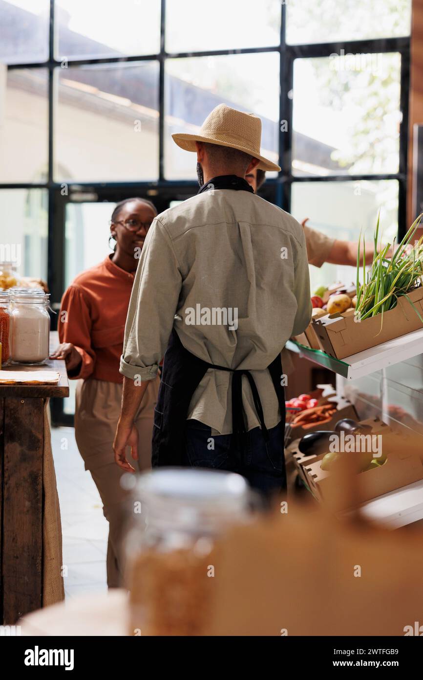 Shopkeeper providing expert advice to diverse couple as they shop for ...