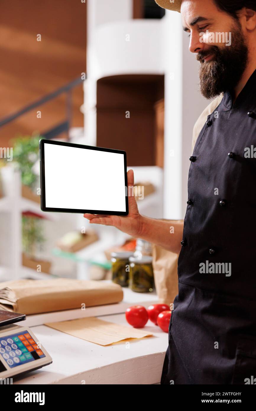 While holding tablet with isolated white screen, male shopkeeper waits ...