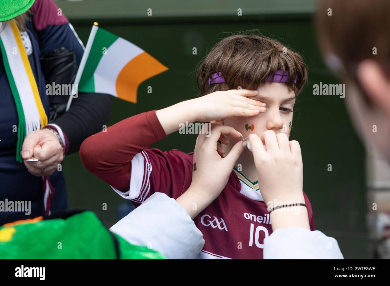 London, UK. 17th Mar, 2024. A child is seen getting a temporary Irish ...