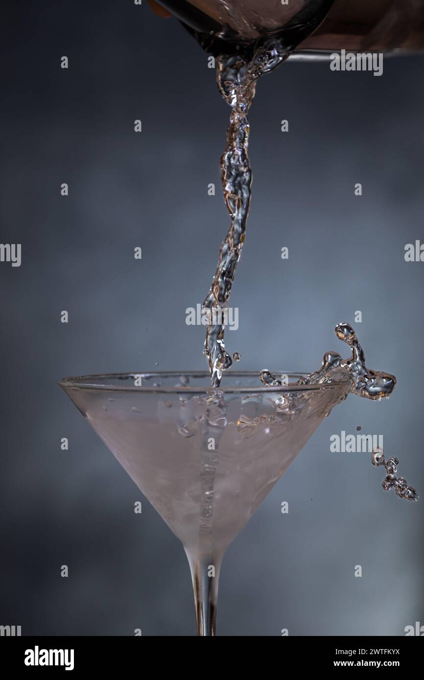 Action shot of pouring chilled vodka into a martini glass over a ...