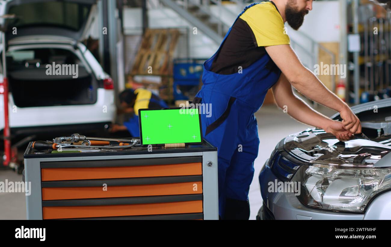 Panning shot of green screen laptop in garage workspace, sitting on ...