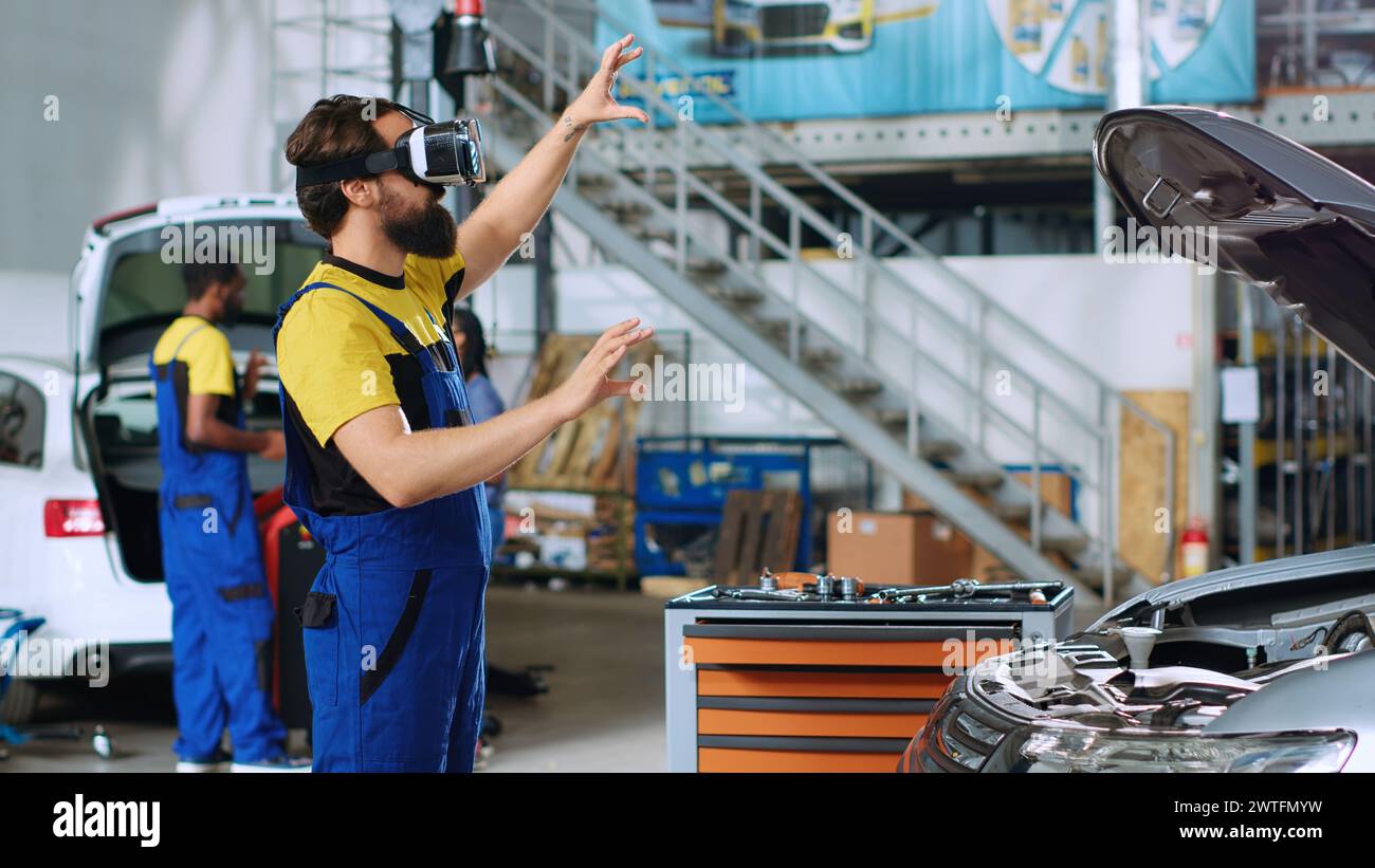 Qualified serviceman in auto repair shop using virtual reality goggles ...