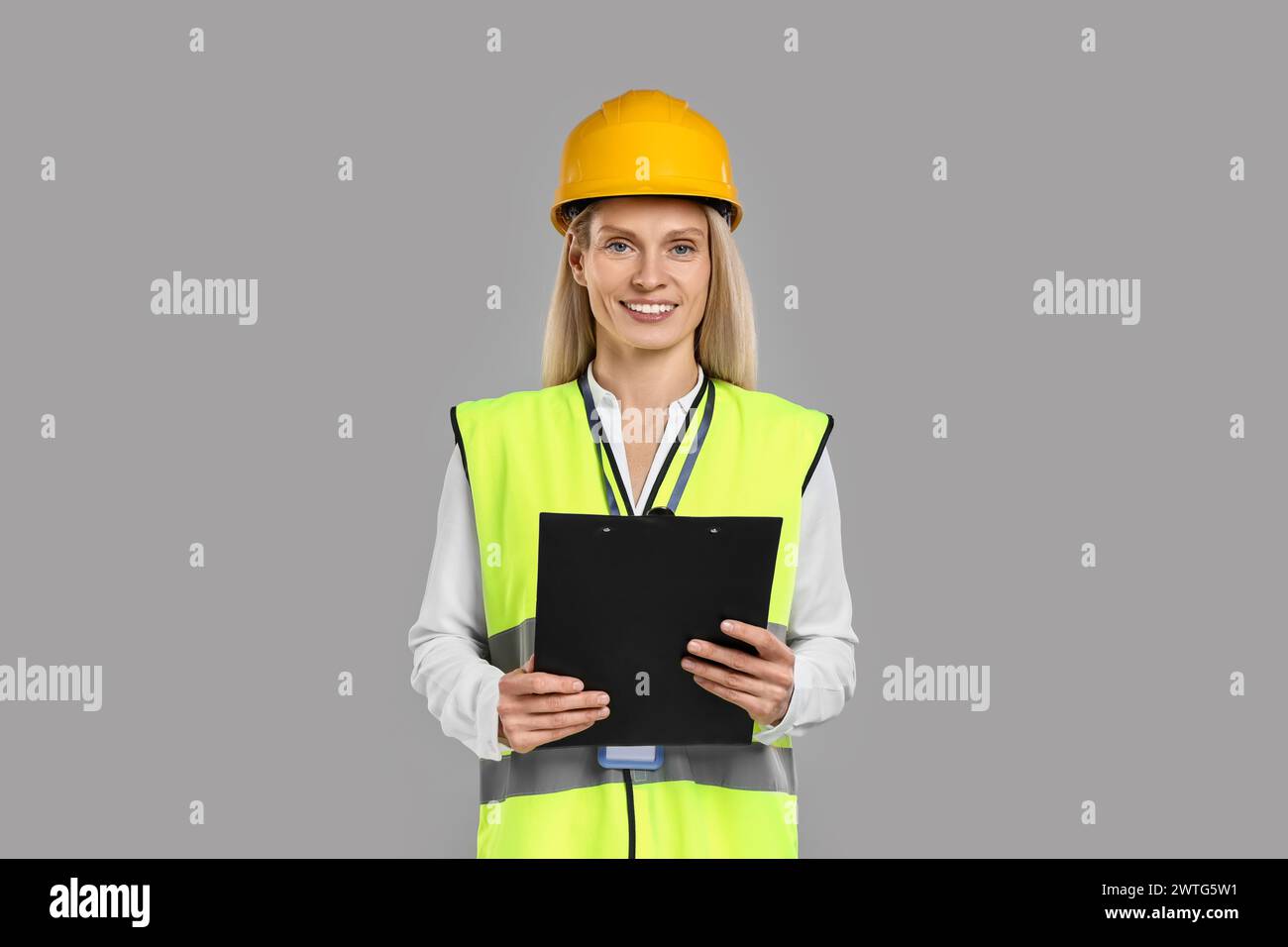 Engineer in hard hat holding clipboard on grey background Stock Photo ...
