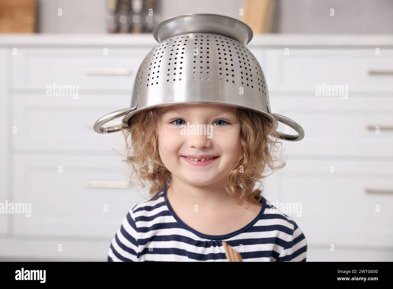Cute little girl with colander on her head in kitchen Stock Photo - Alamy