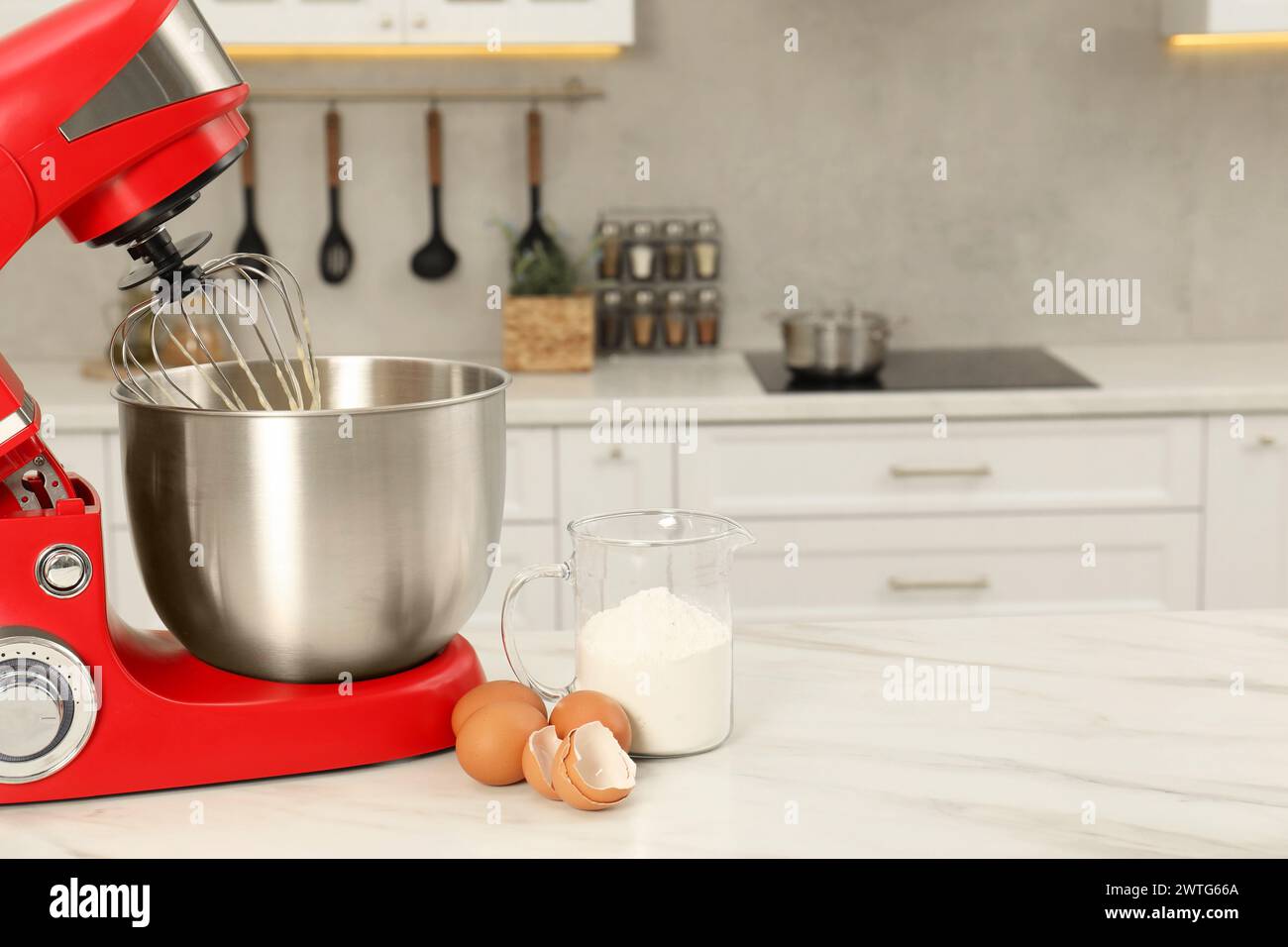 Modern red stand mixer, eggs and container with flour on white marble ...