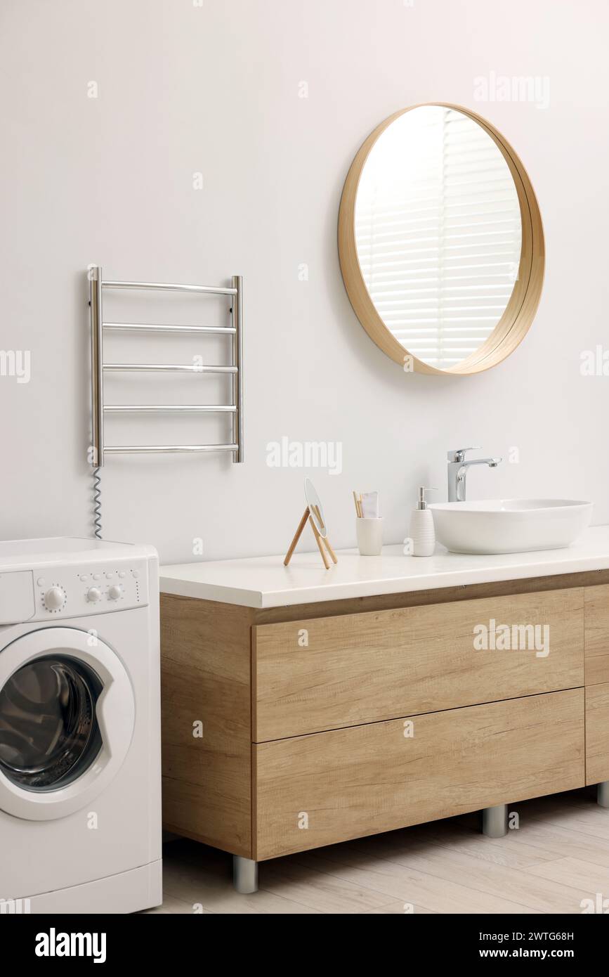 Stylish bathroom interior with heated towel rail and washing machine ...