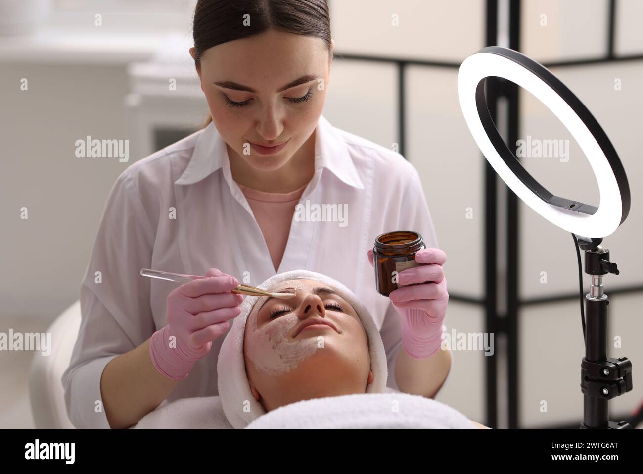 Cosmetologist applying mask on woman's face in clinic Stock Photo - Alamy