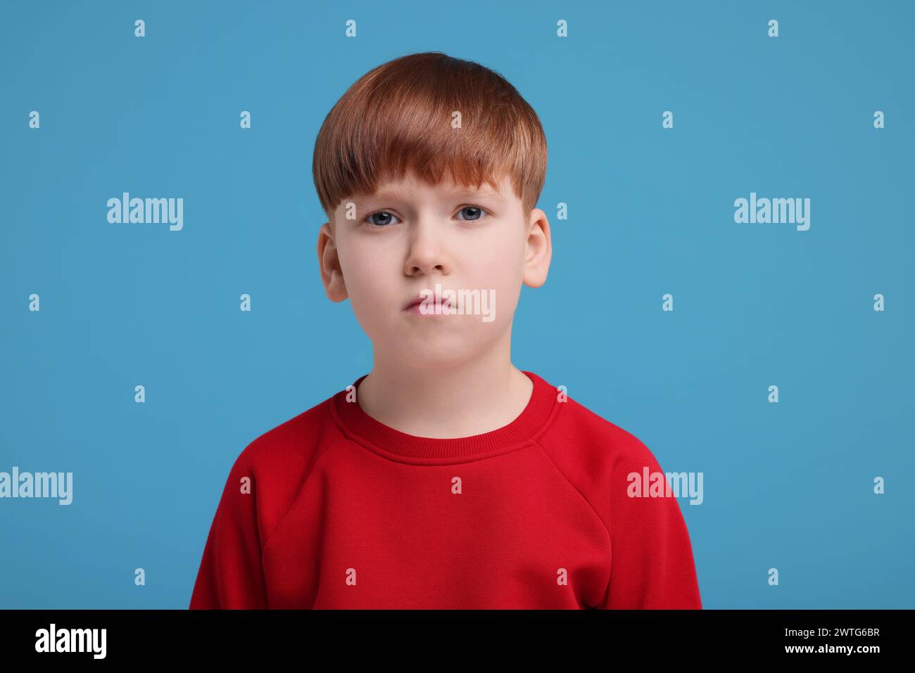 Portrait of sad little boy on light blue background Stock Photo - Alamy