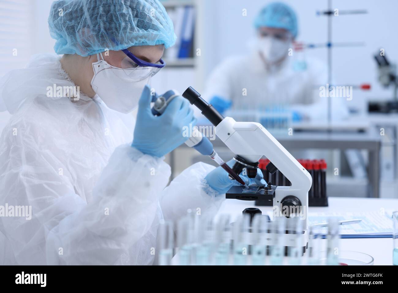 Scientist dripping sample onto glass slide while working with ...