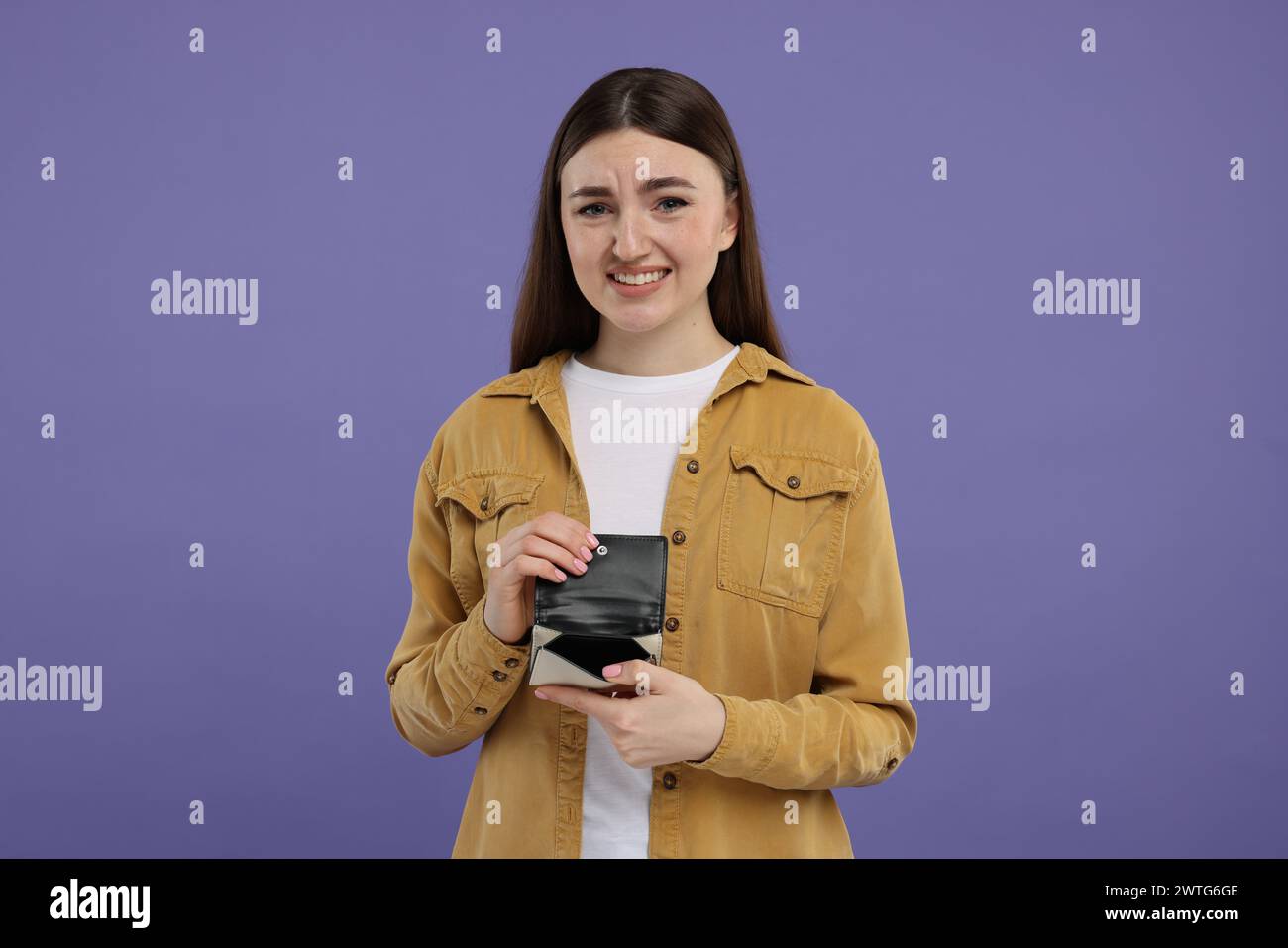 Woman showing empty wallet on purple background Stock Photo - Alamy