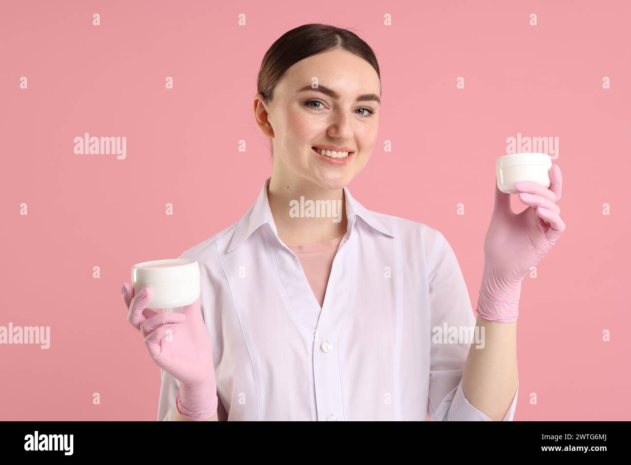 Cosmetologist with cosmetic products on pink background Stock Photo - Alamy