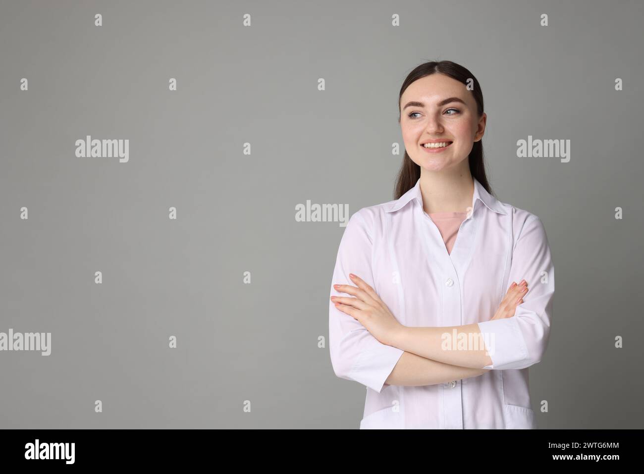 Cosmetologist in medical uniform on grey background, space for text ...