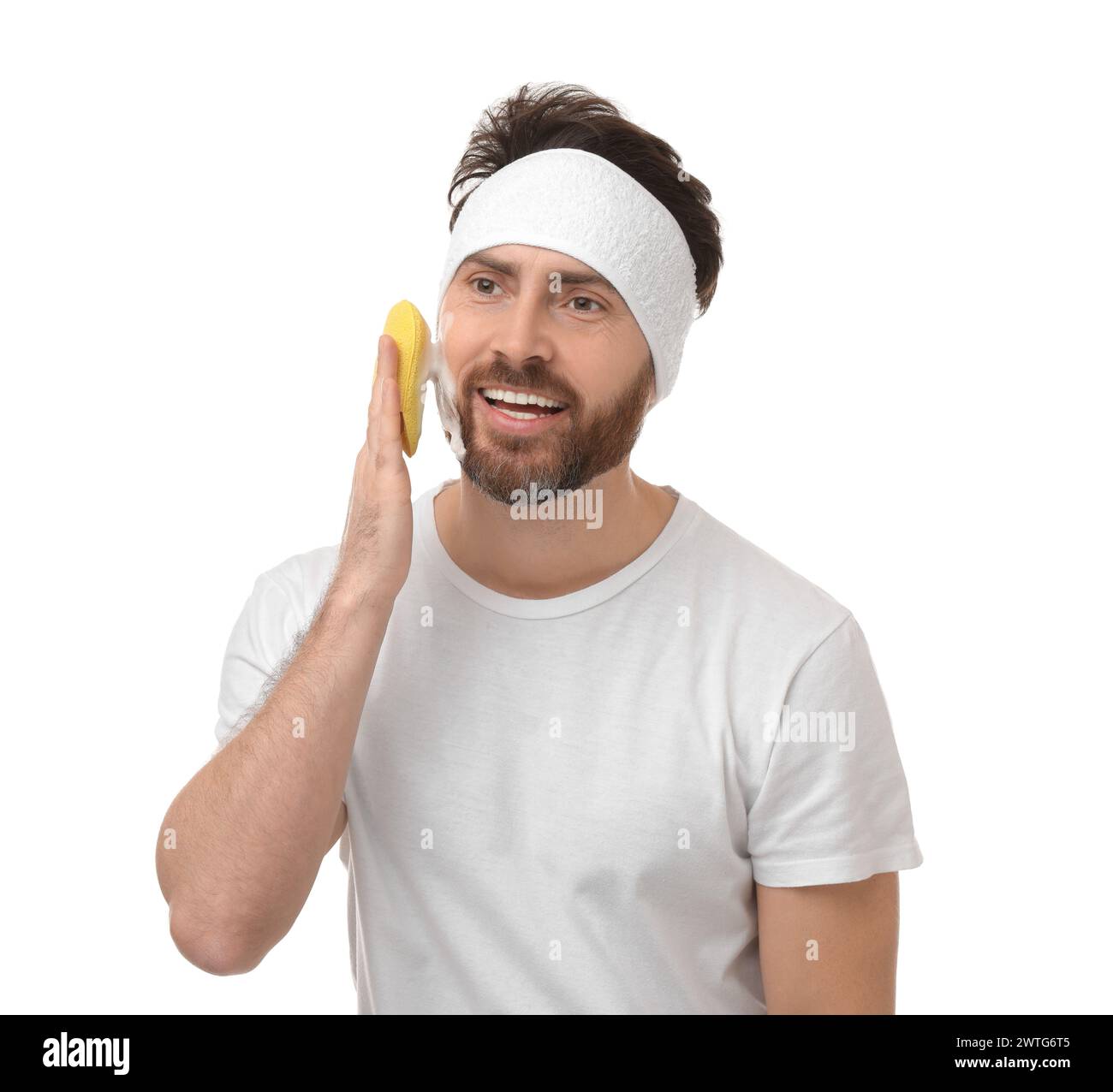 Man with headband washing his face using sponge on white background ...