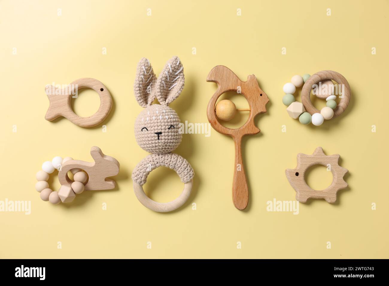 Baby accessories. Rattles and teethers on yellow background, flat lay ...