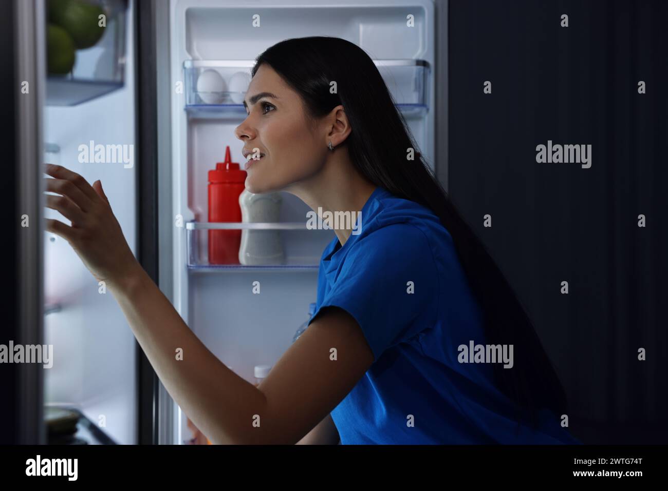 Young smiling woman looking into modern refrigerator at night Stock ...