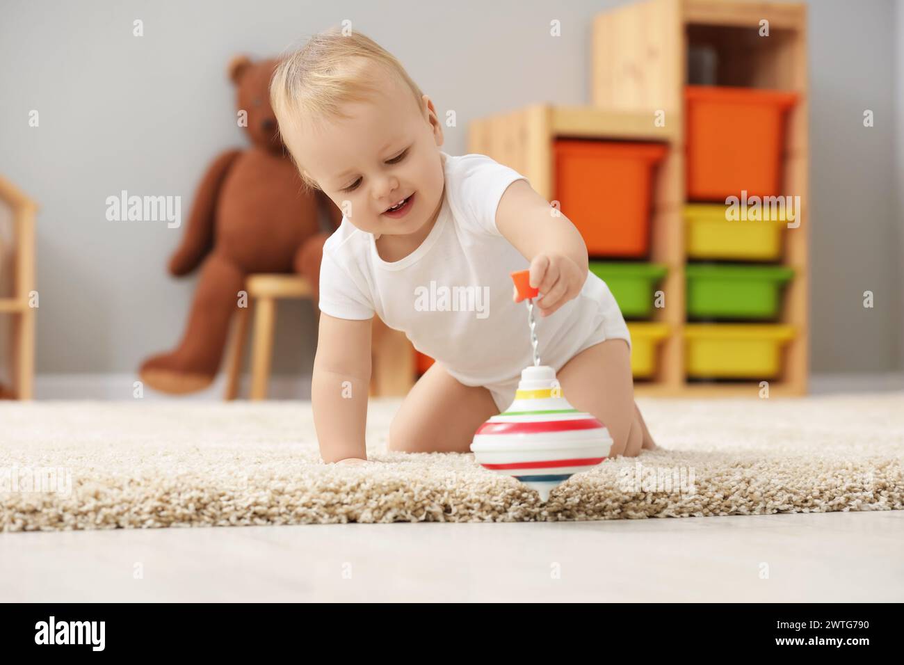 Children toys. Cute little boy playing with spinning top on rug at home ...