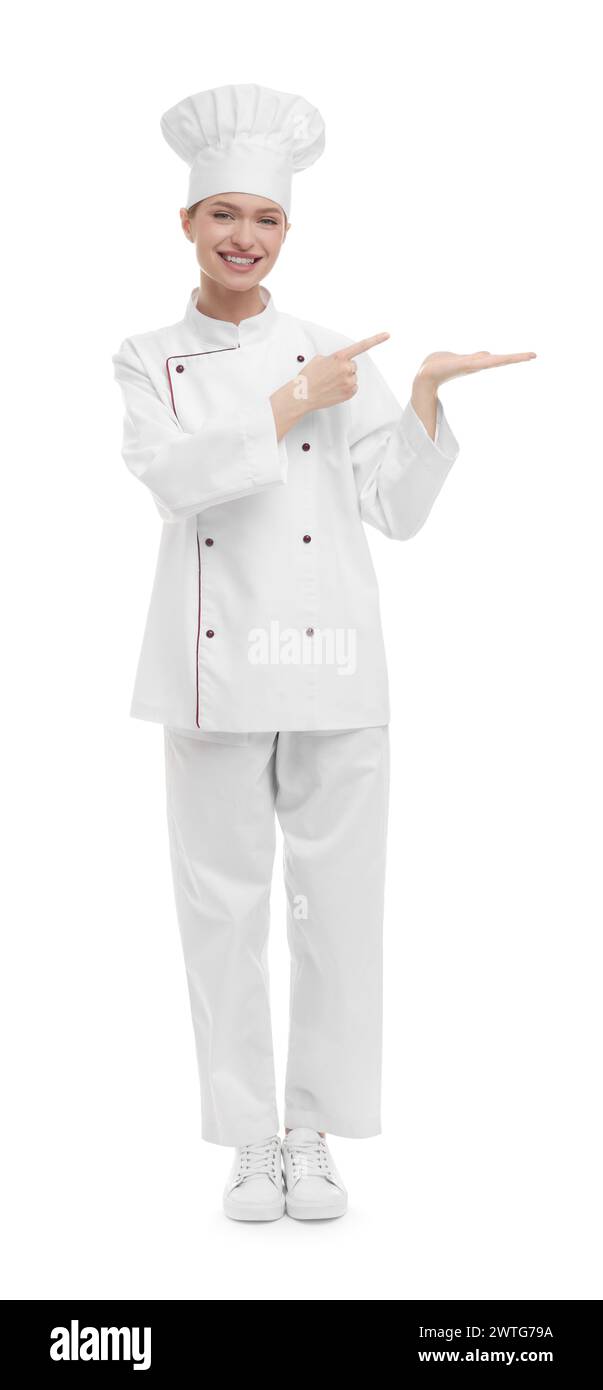 Happy woman chef in uniform pointing at something on white background ...