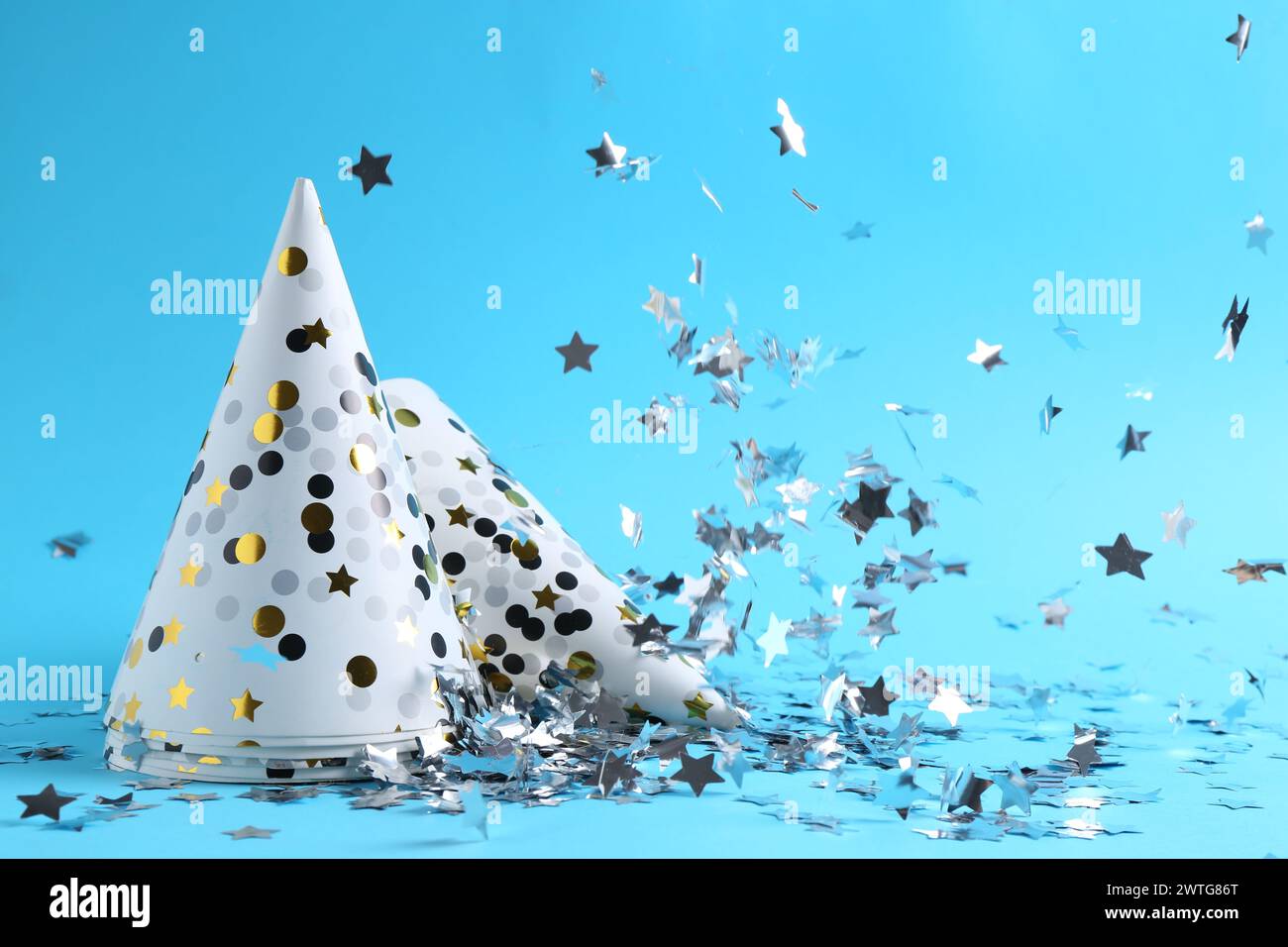 Party hats and confetti on light blue background Stock Photo - Alamy