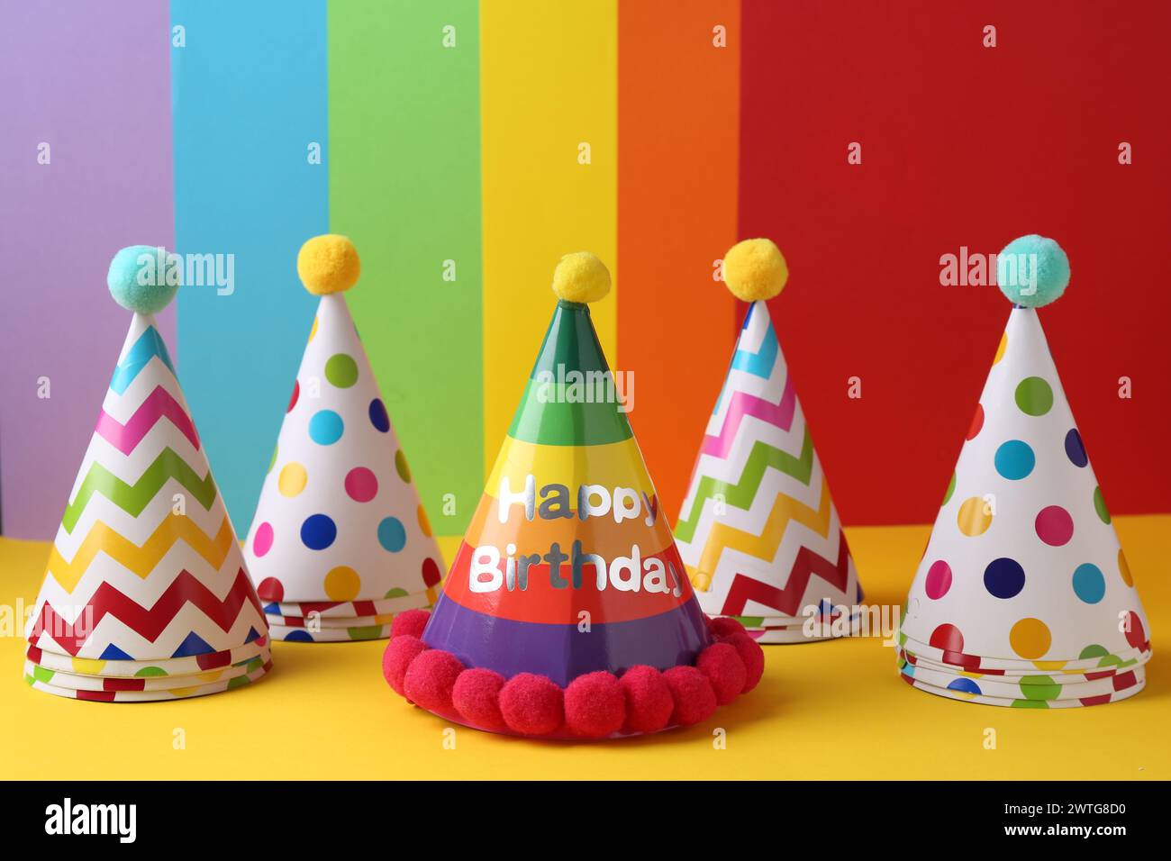Different bright party hats with pompoms on color background Stock ...