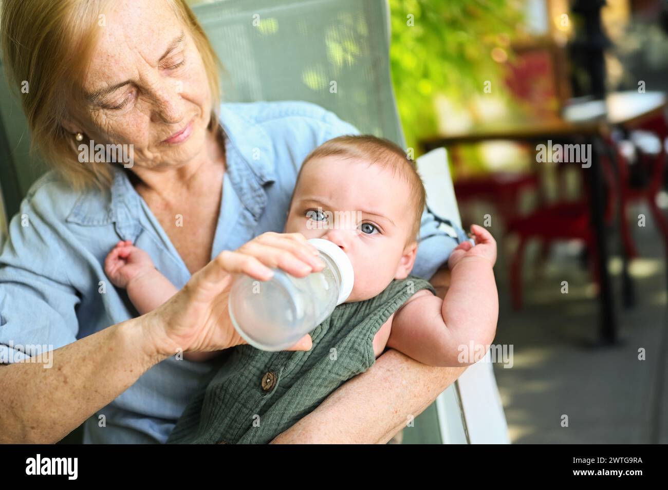 Beautiful happy smiling senior elderly woman nanny feeding formula on ...