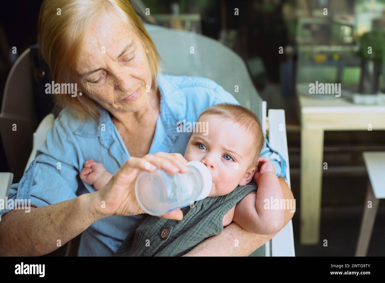 Beautiful happy smiling senior elderly woman nanny feeding formula on ...