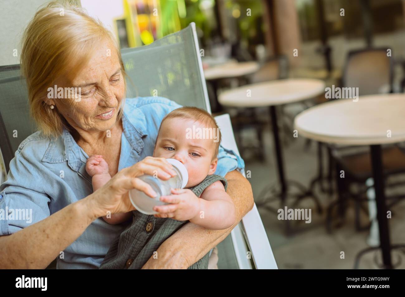 Beautiful happy smiling senior elderly woman nanny feeding formula on ...