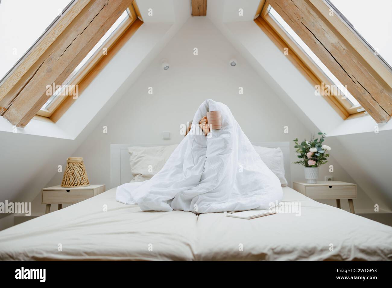 a person is sitting on a bed with a blanket over their head Stock Photo ...